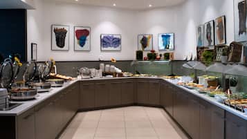 Uma área de buffet com diversos tipos de comida e obras de arte nas paredes.