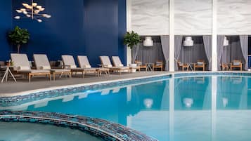Uma área interna moderna com piscina, espreguiçadeiras e parede de mármore.