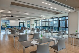 Uma sala de conferência moderna com mesas, cadeiras e amplas janelas.