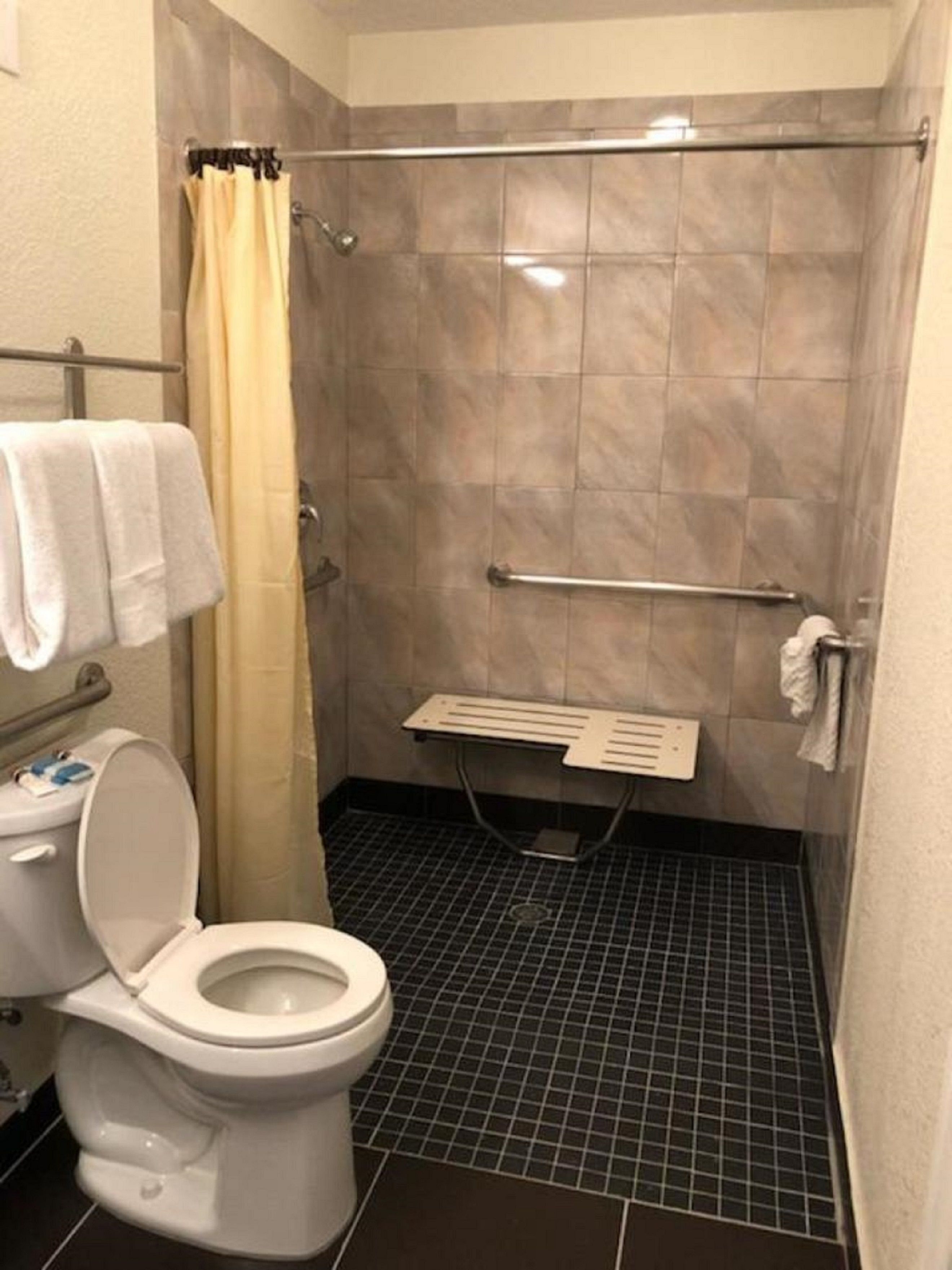 Um banheiro com vaso sanitário, chuveiro com porta de vidro e porta-toalhas.