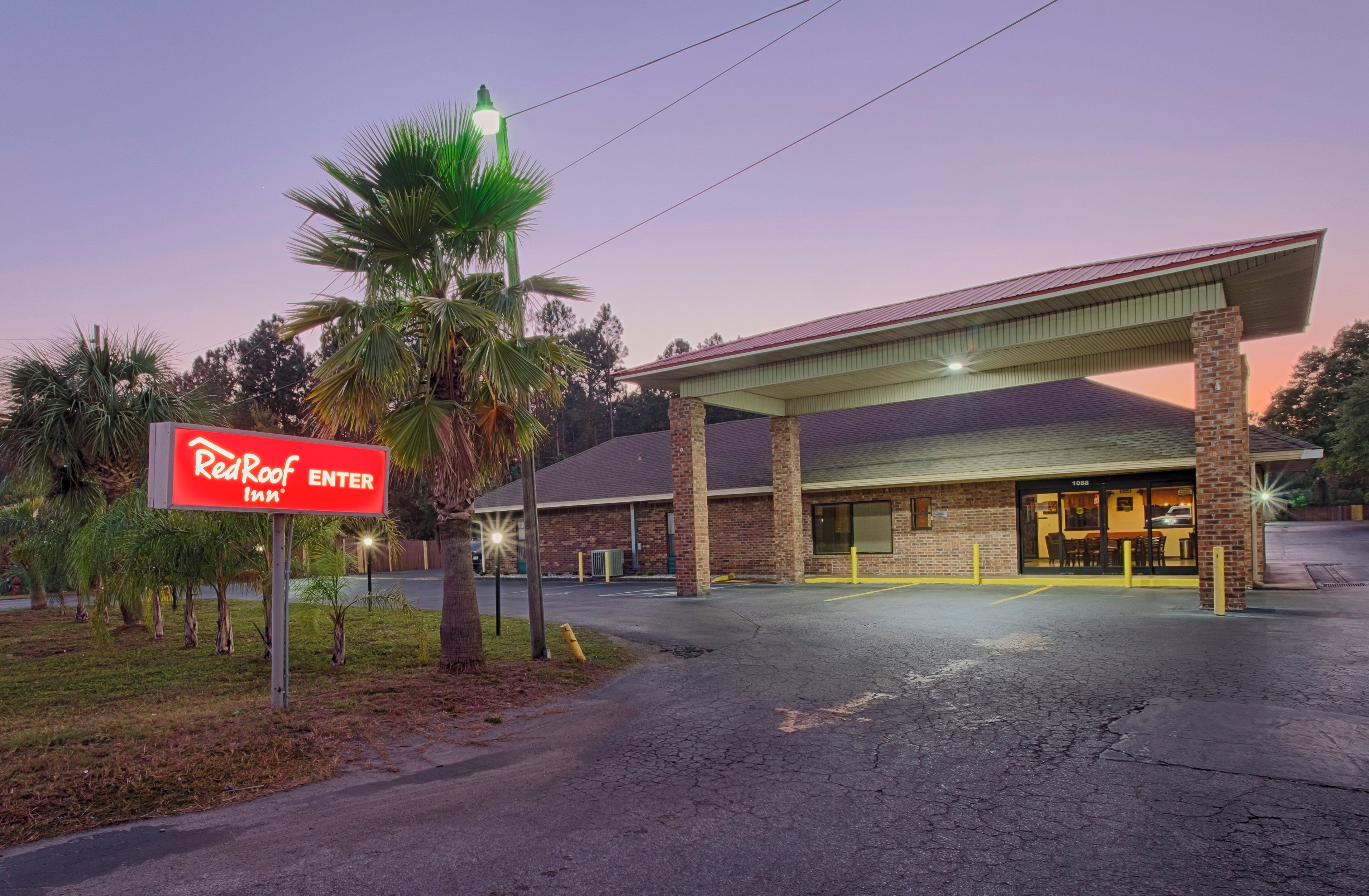 Um RedRoof Inn com fachada de tijolos, área de estacionamento coberta e um lampião.