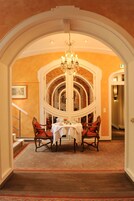 Uma sala de jantar com mesa branca, cadeiras vermelhas e um lustre.