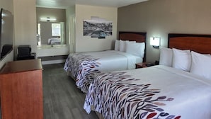 A hotel room with two beds, a desk, a television, and a window.