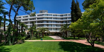 Hotel de vários andares com design moderno, cercado por vegetação exuberante e palmeiras.