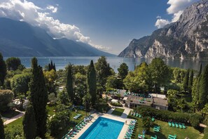 Um resort com piscina, espreguiçadeiras e vista para um lago e montanhas.