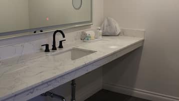 Uma casa de banho moderna com um espelho grande, lavatório de mármore branco e um porta-toalhas.