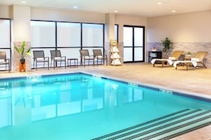 Piscina interna com espreguiçadeiras e porta-toalhas.