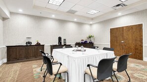 Sala de conferências com uma mesa redonda, cadeiras, espaço para café e uma porta.