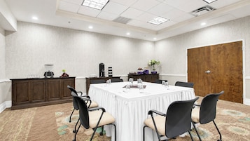 Sala de conferências com uma mesa redonda, cadeiras, espaço para café e uma porta.