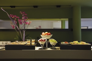 Disposição de buffet com diversos alimentos e um arranjo ornamental de orquídeas.