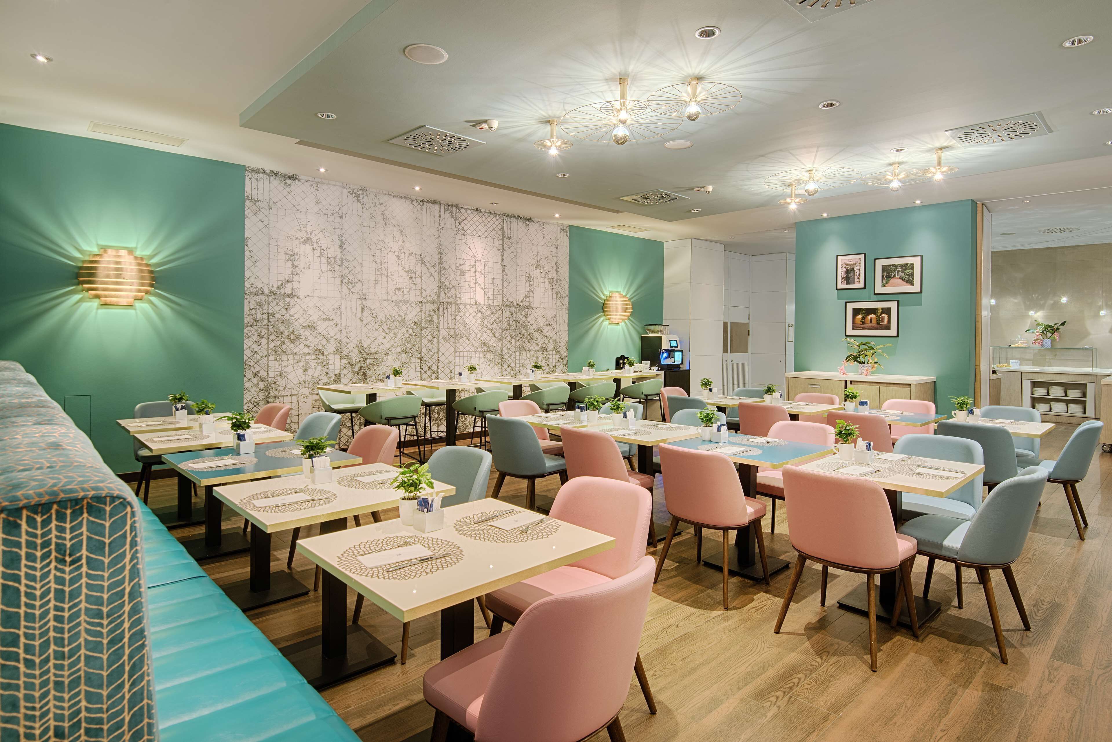 Uma sala de jantar moderna com paredes verde-água, várias mesas e cadeiras.