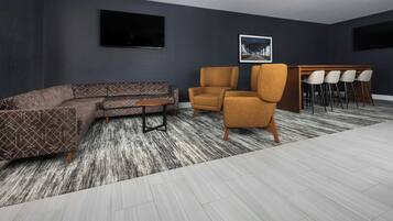 Uma área de estar moderna com sofá seccional, poltronas, uma pequena mesa e um bar com bancos.
