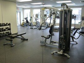 Uma academia com diversos equipamentos de exercícios, incluindo esteiras, aparelhos de musculação e halteres.
