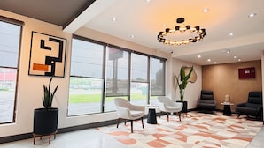 Um hall amplo com grandes janelas, um lustre moderno e áreas de estar.