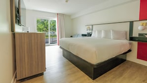 Quarto de hotel moderno com uma cama grande, televisão de tela plana, escrivaninha e vista para o exterior.