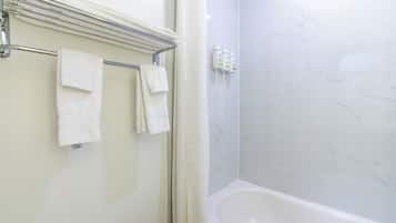 Casa de banho com banheira, um porta-toalhas com vários toalhas e cortina de chuveiro.