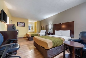 Quarto de hotel com duas camas, uma mesa, uma cadeira e uma televisão.