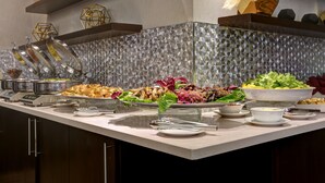 Disposição de buffet com diversos alimentos e utensílios de servir.
