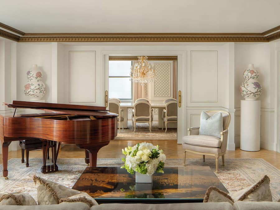 Um piano de cauda, um arranjo floral e uma sala de jantar com um candelabro.