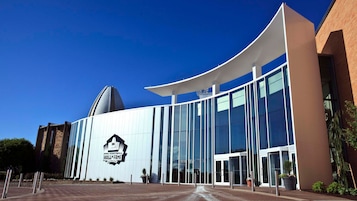 Um edifício moderno com fachada curva, grandes janelas de vidro e o logotipo Pro Football Hall of Fame bem visível.