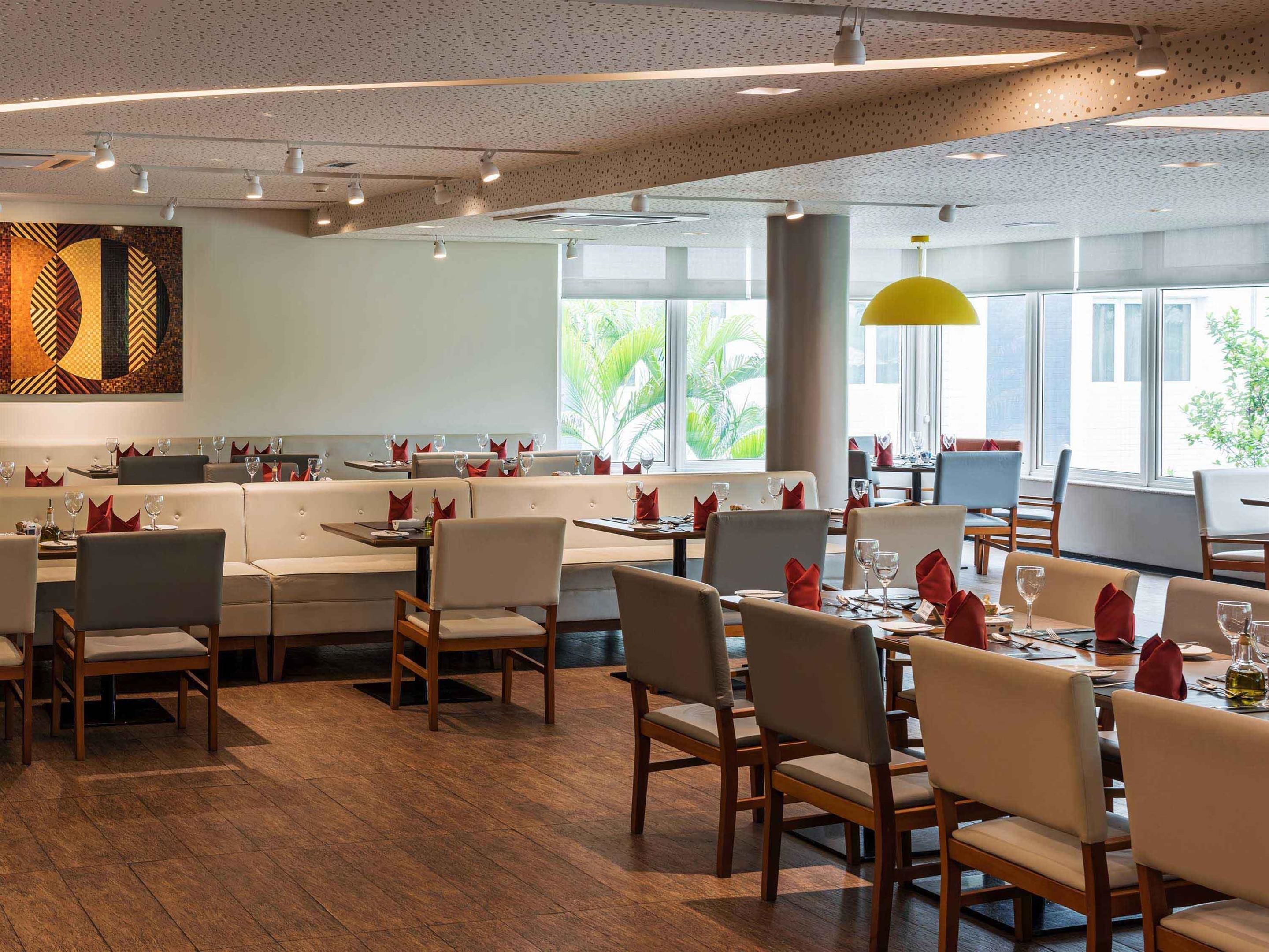 Restaurante moderno com pé-direito alto, piso de madeira e uma combinação de assentos em cabines e mesas.