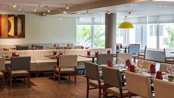 Restaurante moderno com pé-direito alto, piso de madeira e uma combinação de assentos em cabines e mesas.