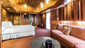 Uma cabana com interior de madeira, uma cama, um sofá e uma pequena mesa com uma xícara.