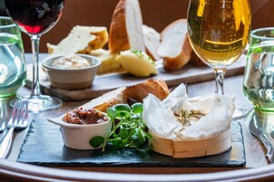 Uma mesa de jantar com diversos alimentos, incluindo pão, queijo e vegetais, além de taças de vinho.