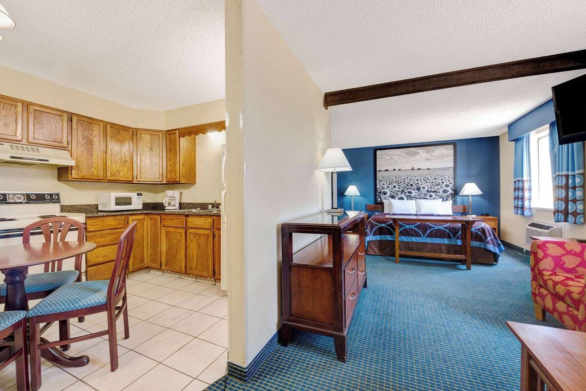 Quarto de hotel compacto com cozinha compacta, área de refeições, cama e banheiro.