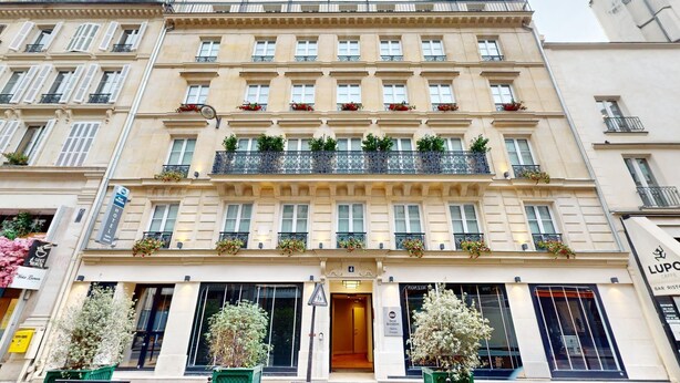 Um hotel de vários andares com arquitetura europeia clássica, destacando uma entrada central, varandas com caixas de flores e uma placa indicando ser um hotel Best Western.