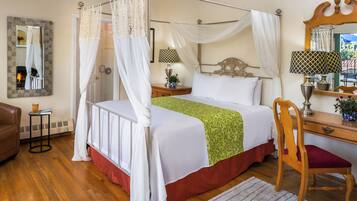 Uma cama com dossel e cortinas, um cobertor verde, uma escrivaninha de madeira com cadeira e um espelho na parede.