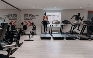 Uma academia com esteiras, bicicletas ergométricas e aparelhos de musculação.