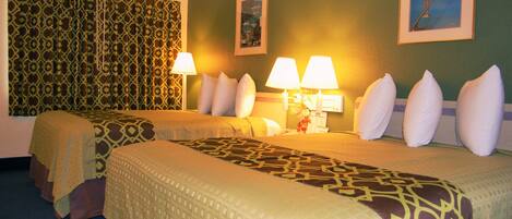 Quarto de hotel com duas camas, colchas estampadas, duas luminárias de cabeceira e cortina padronizada.