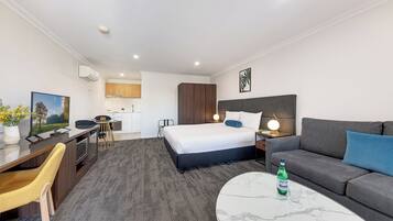 Quarto de hotel com cama, sofá, escrivaninha e espaço para refeições.
