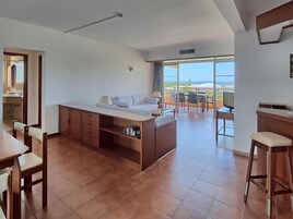 Uma cozinha moderna com área de jantar, um sofá e vista para o mar.