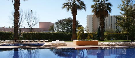 Piscina com espreguiçadeiras e palmeiras.