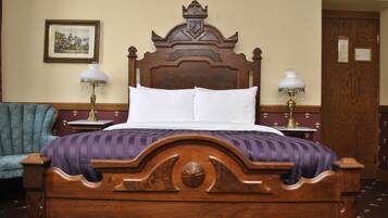Uma cama de madeira com cabeceira decorativa, duas mesas de cabeceira com luminárias e um quadro na parede.
