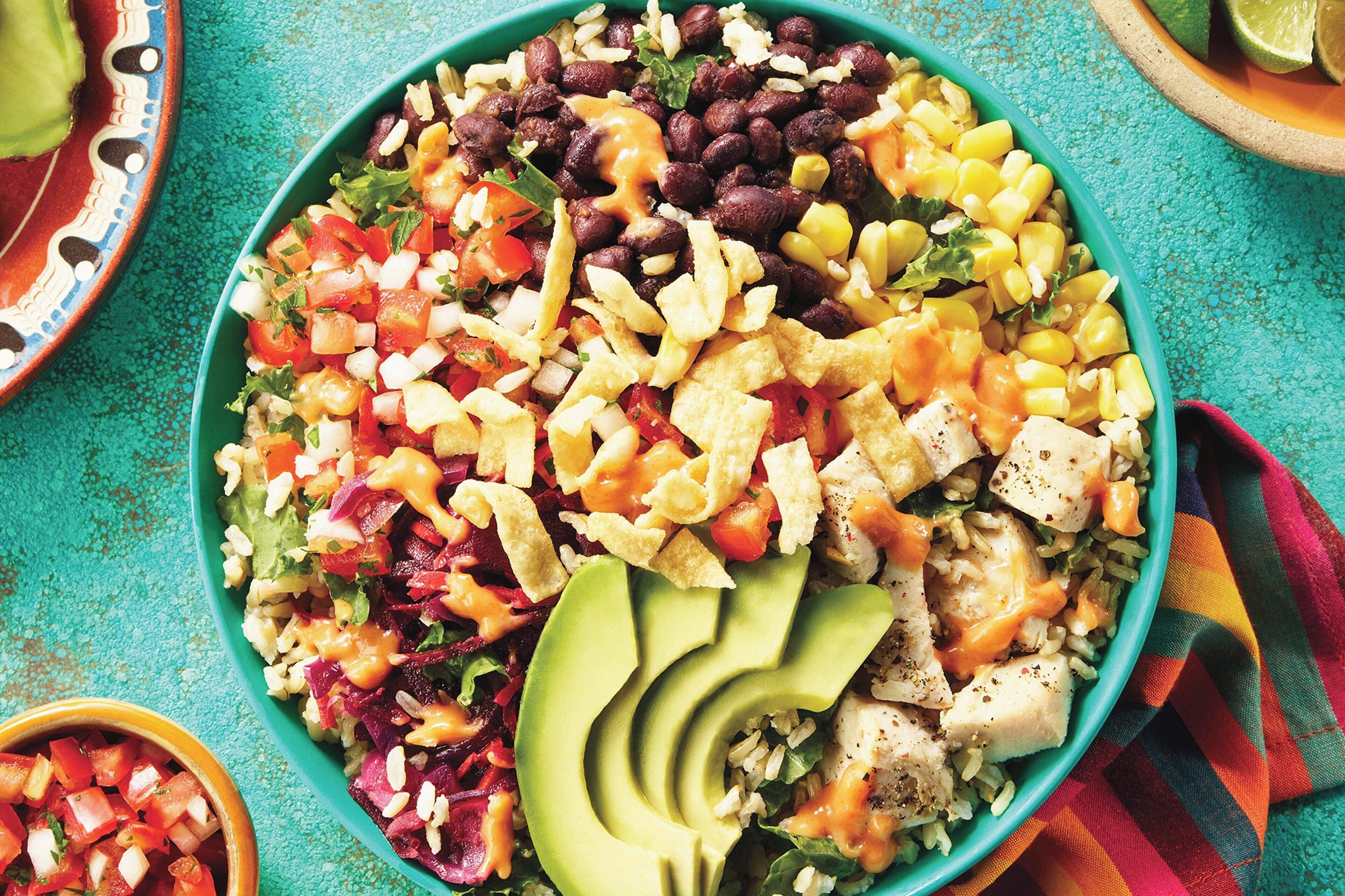 Salada colorida com diversos ingredientes como abacate, feijão, milho e tomate picado.