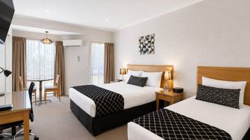 Quarto de hotel com duas camas, uma escrivaninha e uma cadeira.