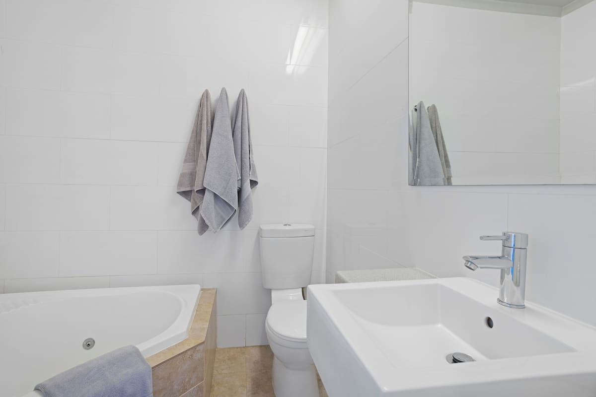 Uma casa de banho moderna com banheira, sanita e lavatório.