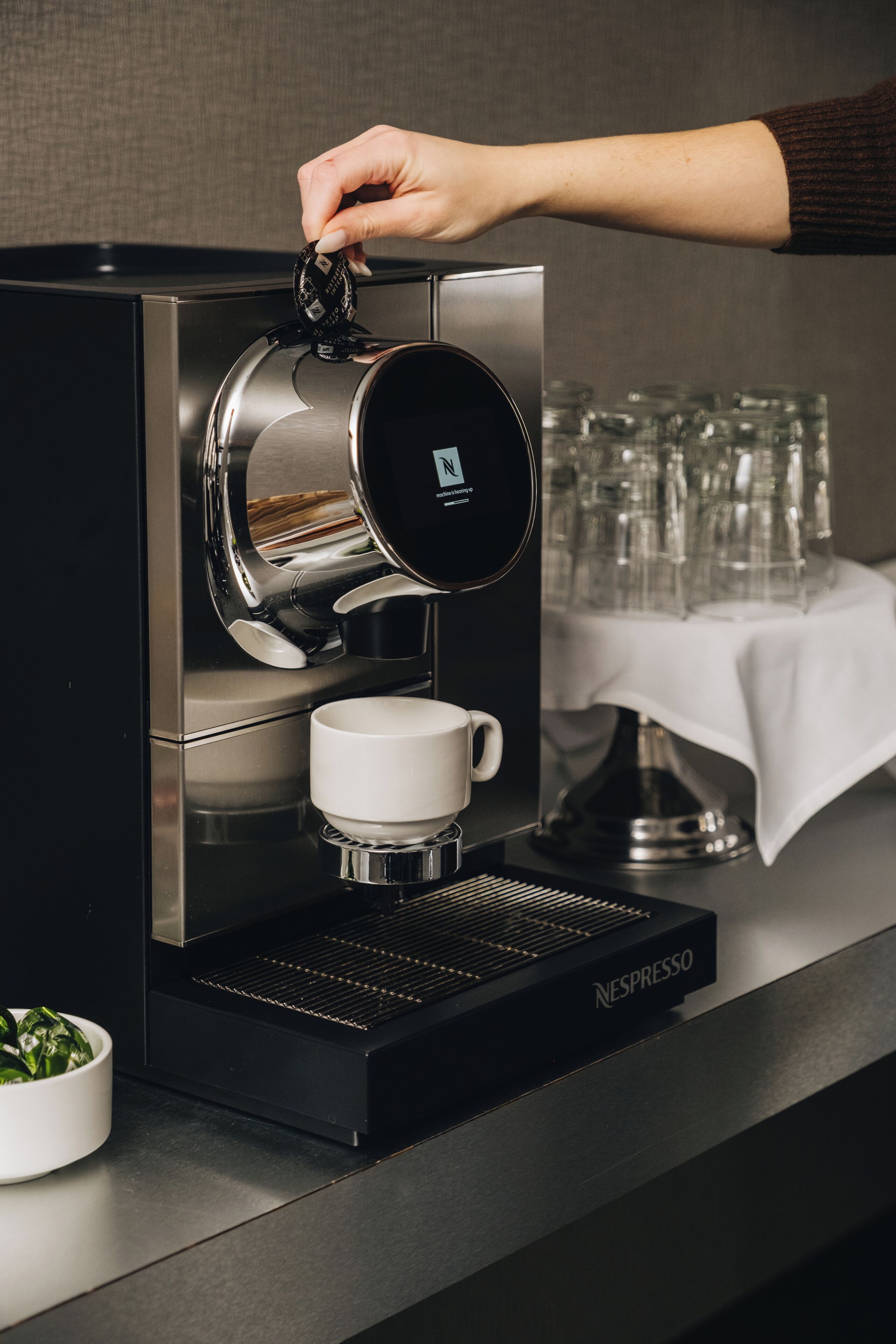 Máquina de café Nespresso com uma mão a servir café numa chávena.