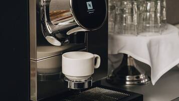 Máquina de café Nespresso com uma mão a servir café numa chávena.