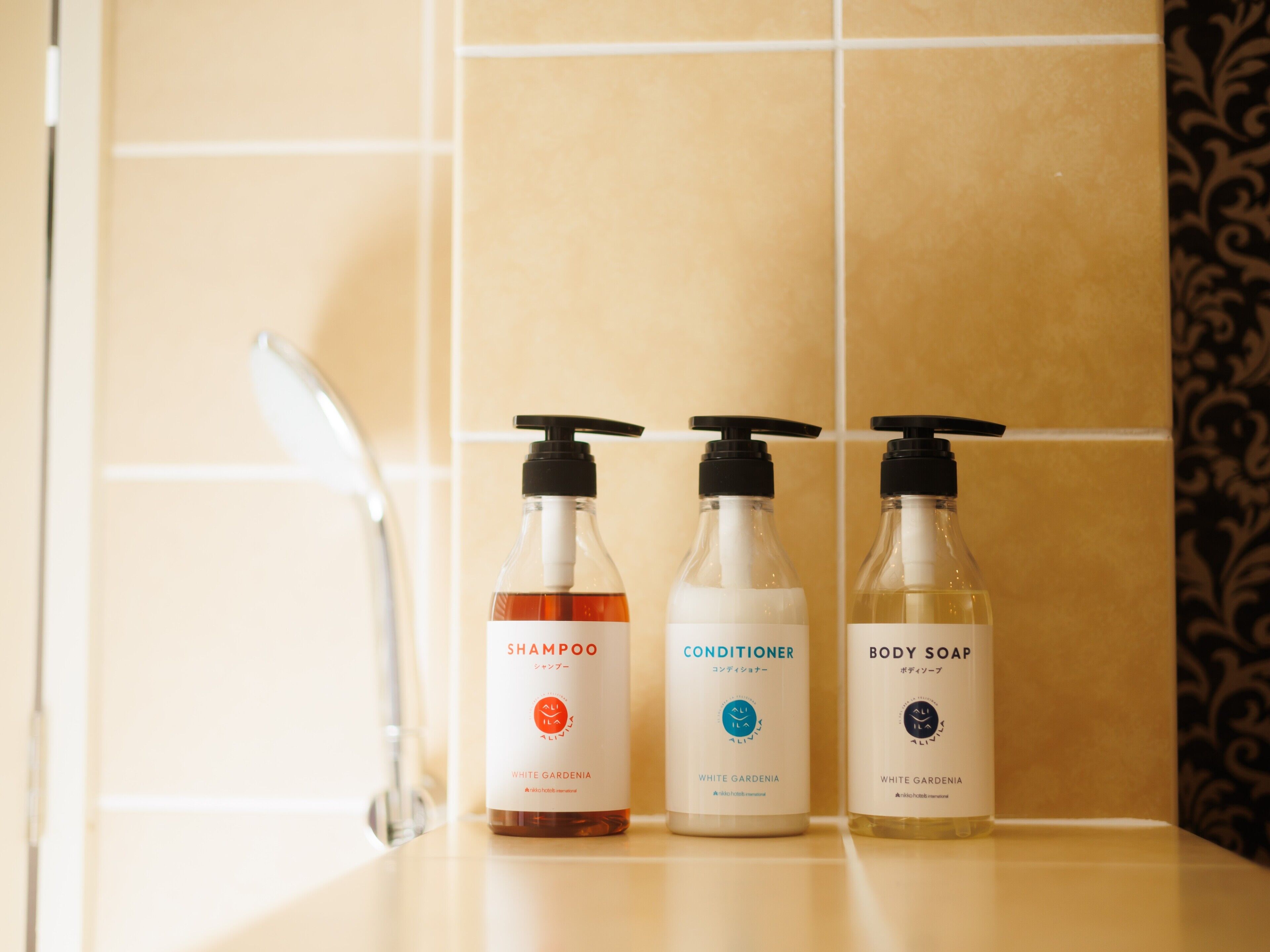 Três frascos de shampoo, condicionador e sabonete White Gardenia em uma bancada de banheiro.