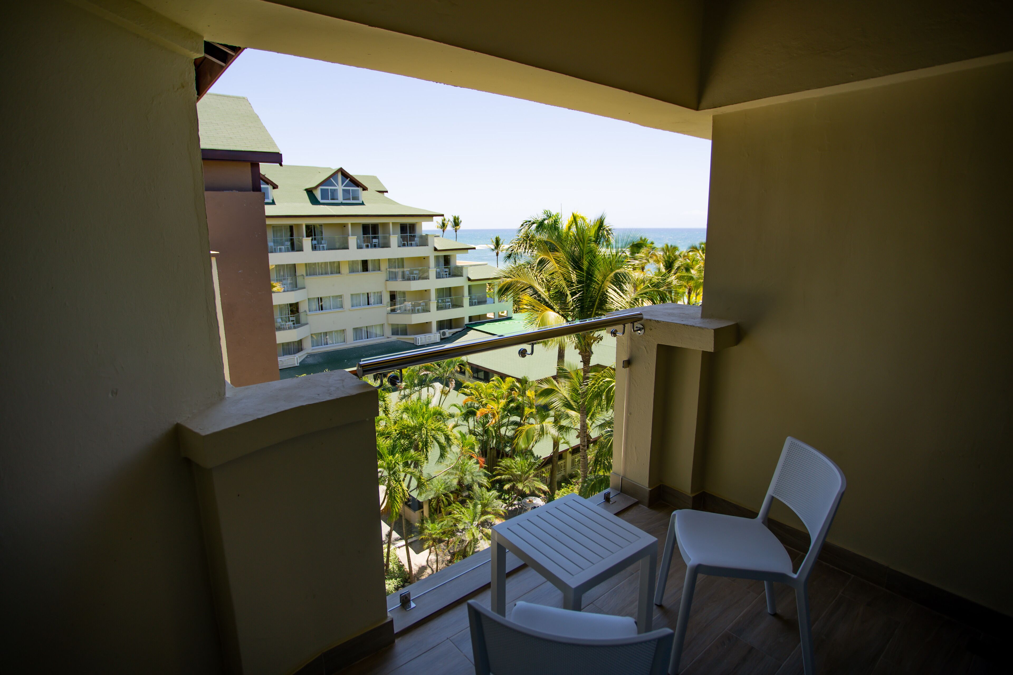 Varanda com mesa e cadeira, com vista para uma piscina e um edifício com várias varandas.