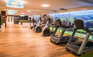 Uma academia com várias esteiras alinhadas junto a uma parede com vista panorâmica.