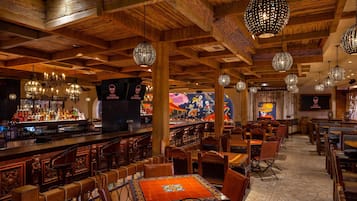 Um restaurante com vigas de madeira no teto, luminárias pendentes esféricas e um bar com garrafas.