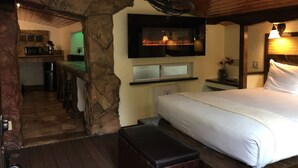 Um quarto aconchegante com um pilar de pedra, uma cama, uma mesinha de cabeceira e um ventilador de teto.
