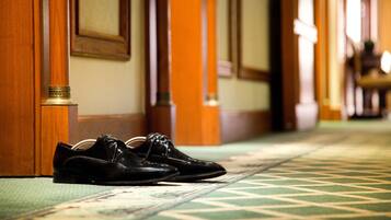 Um par de sapatos sobre um tapete estampado em um corredor com portas de madeira e carpete verde.