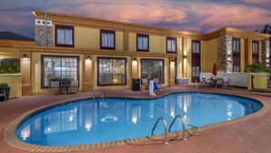 Um hotel com piscina, área de estar ao ar livre e céu ao pôr do sol.