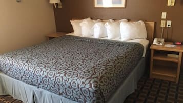 Quarto de hotel com cama, mesa de cabeceira, abajur e quadro na parede.